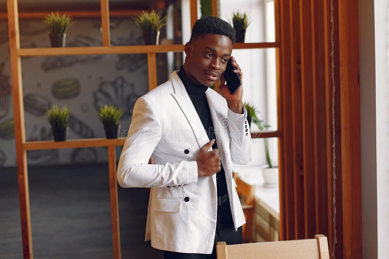 Black Man in a White Jacket Standing with a Phone Stock Photo - Image ...