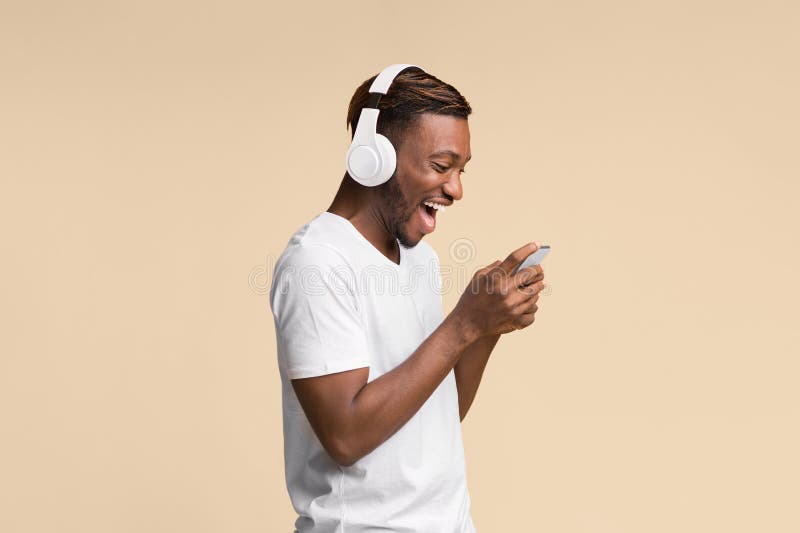 Black Man in Wireless Headphones Using Smartphone in Studio Stock Image ...