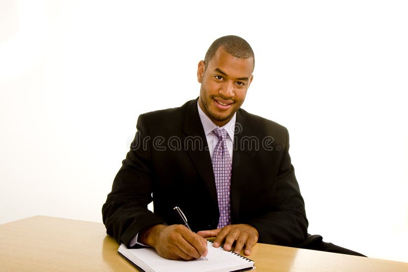 Black Man Writing at Desk and Looking at Camera Stock Image - Image of ...