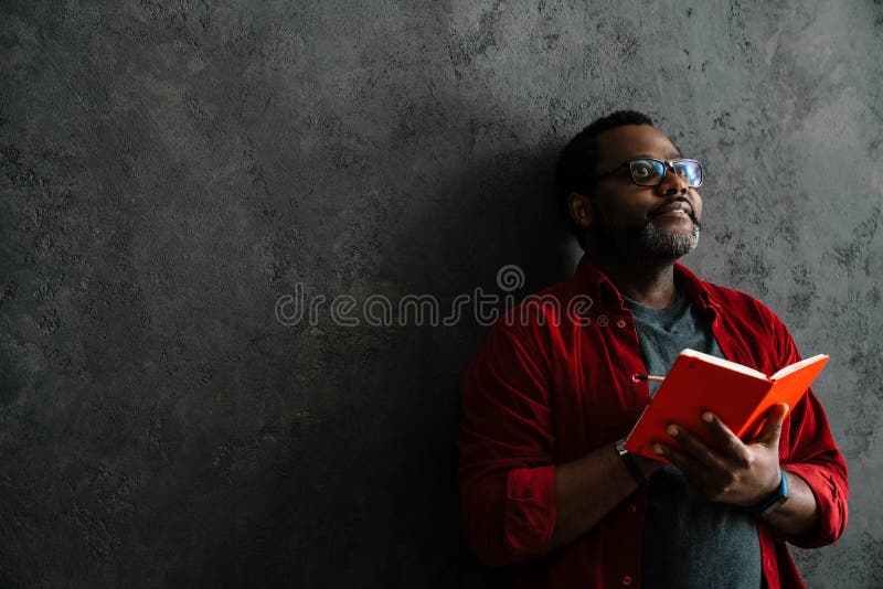 Black Man Writing Down Notes while Leaning on Concrete Wall Stock Image ...