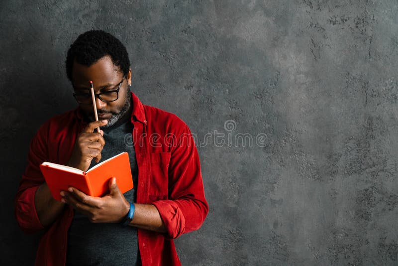 Black Man Writing Down Notes while Leaning on Concrete Wall Stock Image ...