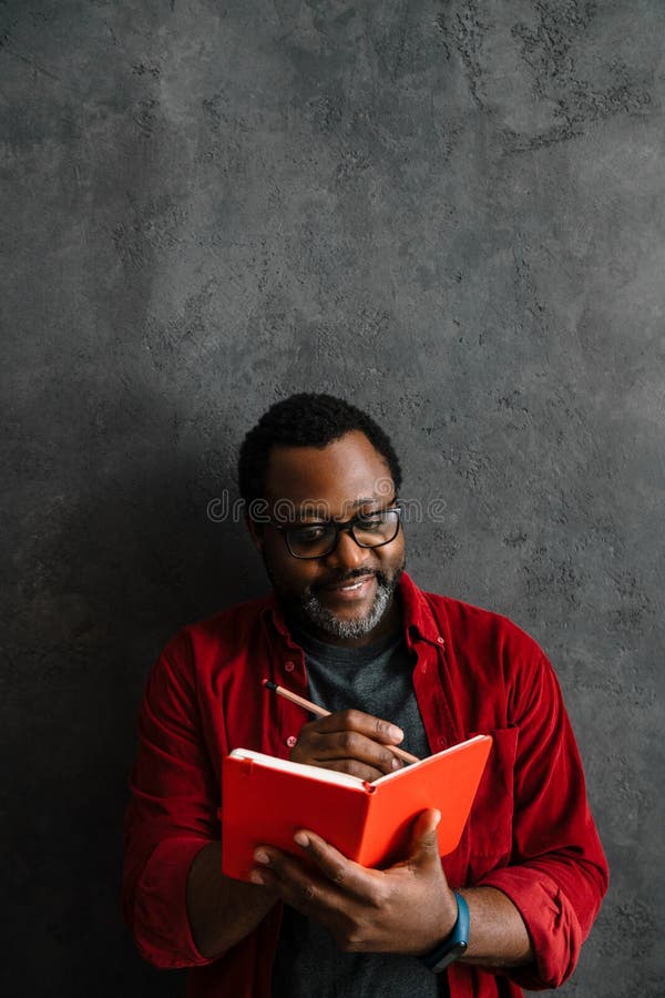 Black Man Writing Down Notes while Leaning on Concrete Wall Stock Photo ...