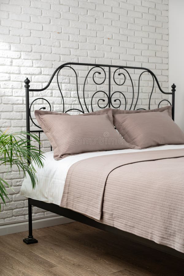 Black Metal Bed Frame with Ornate Headboard and Tan Bedding Stock Photo ...