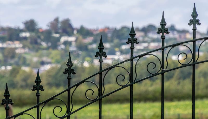 Black Metallic Gate of a Park with Blurred Greenery and Buildings on ...