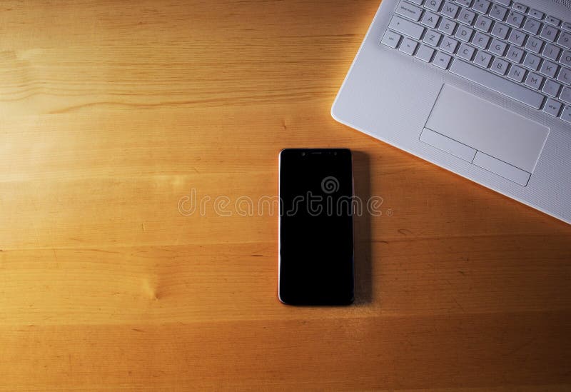 Black Mobile Phone and Computer with White Keyboard on Top of a Wooden ...