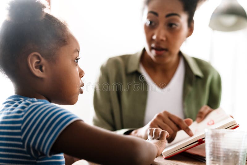 Black Mother Reading with Her Daughter at Table in Home Kitchen Stock ...