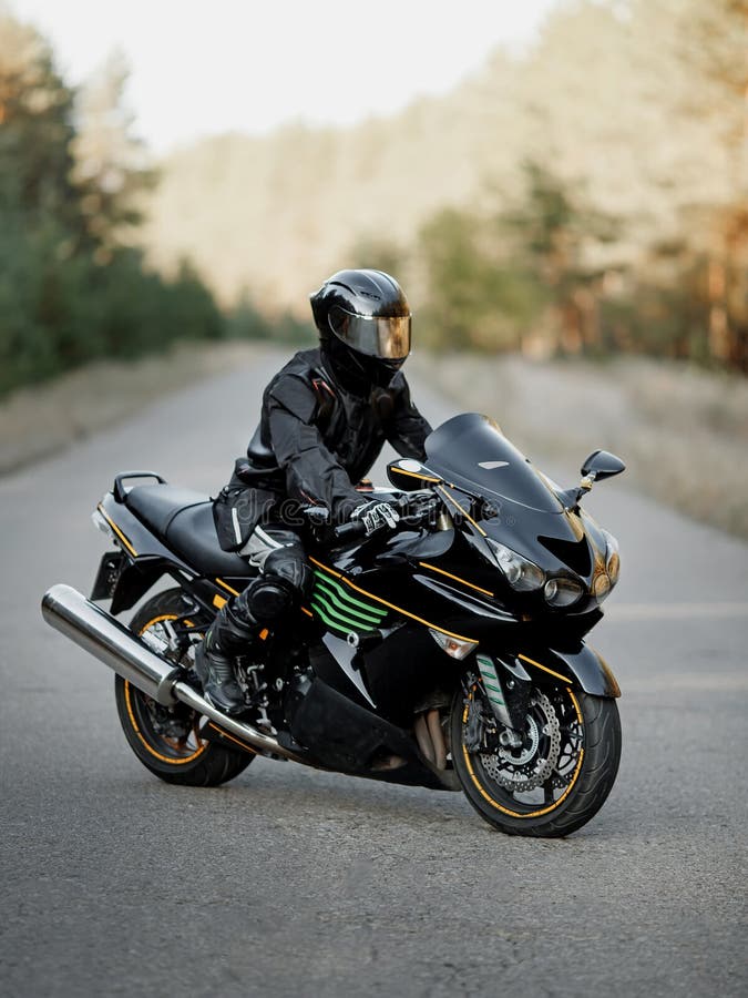 Black Motorcycle Driver in Helmet on Road with Blurred Background Stock ...