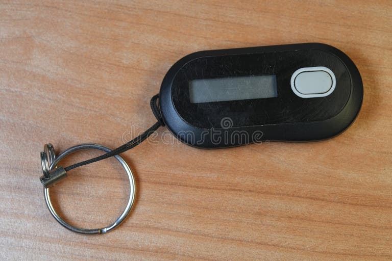 A Black Security Token Dongle Rests on a Wood Surface with a Metal ...