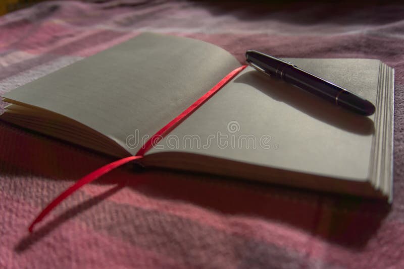 Black Pen and a Notebook Lie on a Red Checked Blanket Stock Photo ...