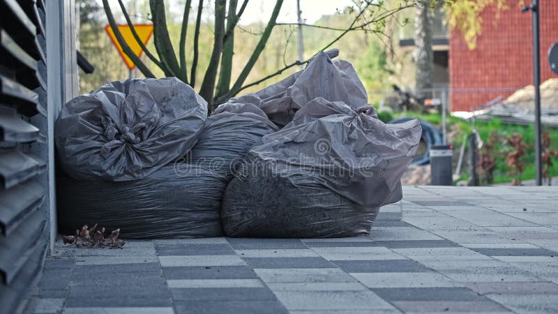 Black Plastic Garbage Bags Stacked on Sidewalk by Dumpster Room Door ...