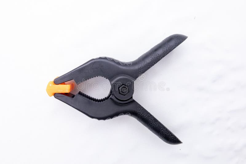 Black Plastic Spring Clamp with Orange Tips Lying on White Marble ...