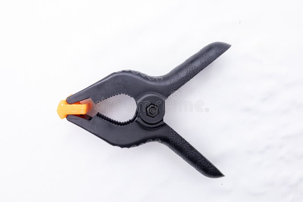 Black Plastic Spring Clamp with Orange Tips Lying on White Marble ...