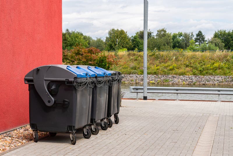 Black Plastic Trash Cans Closed on a Chain Stand Near a Large Red ...