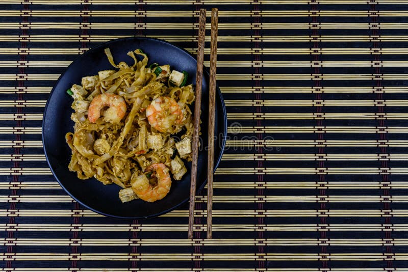 Black Plate with Pad Thai and Chopsticks on a Bamboo Mat. Top View ...