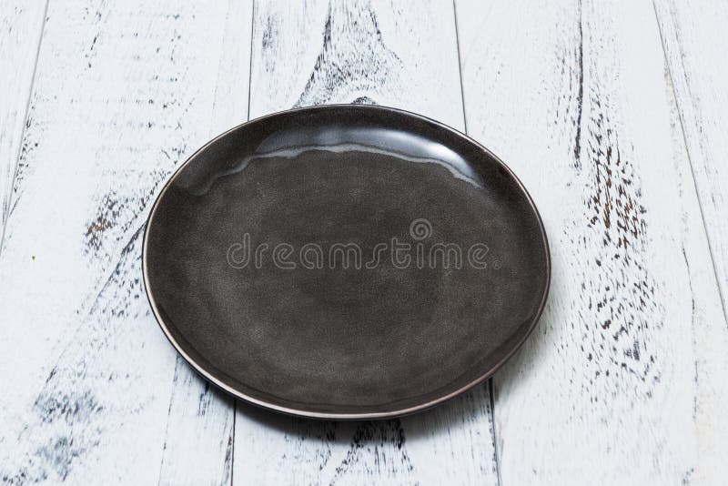 Black Plate on White Scraped Wooden Background Side View Stock Image ...