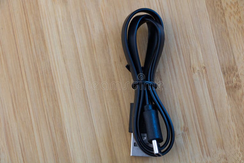 A Black Power Cable with an Integrated Plug is Lying on the Wooden ...