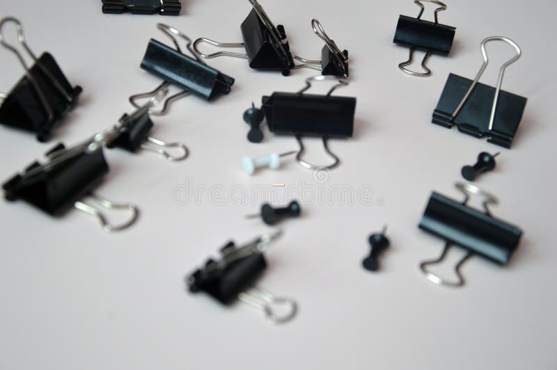 Black Push Pins and Document Clips and Buttons Scattered on a White ...