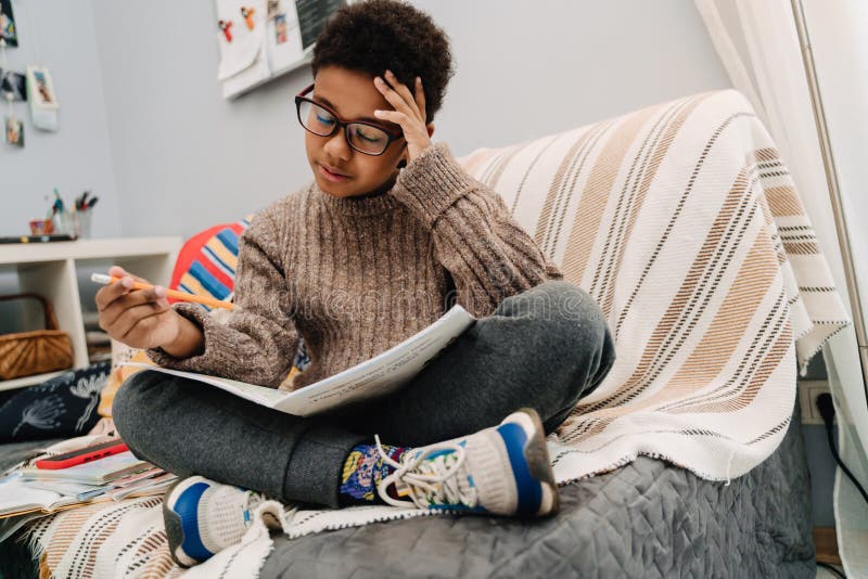 Black Puzzled Boy Doing Homework while Sitting on Sofa Stock Image ...