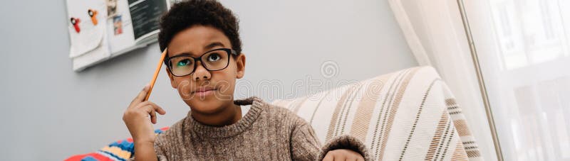 Black Puzzled Boy Doing Homework while Sitting on Sofa Stock Image ...