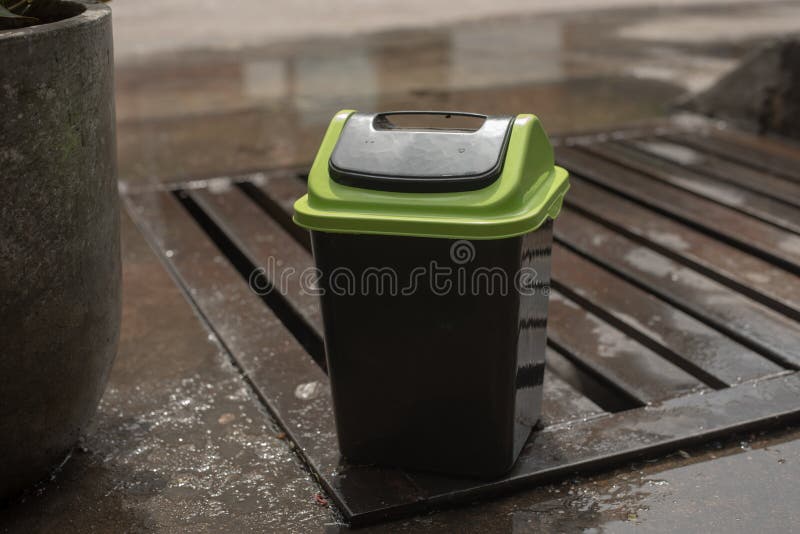A Black, Rectangular Trash Can is Placed. Outside of the House To Put ...