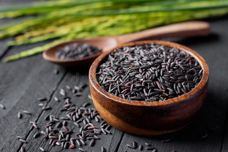 The Black Rice Grains in a Cup are Placed on a Black Wooden Table Stock ...