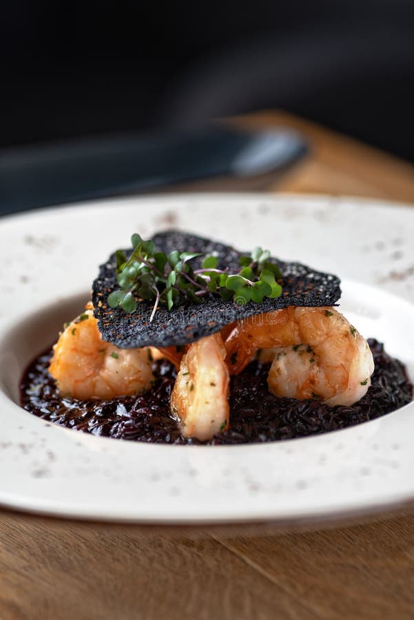 Black Rice Risotto. Shrimp Risotto on a White Plate on the Table ...