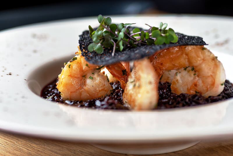 Black Rice Risotto. Shrimp Risotto on a White Plate on the Table ...