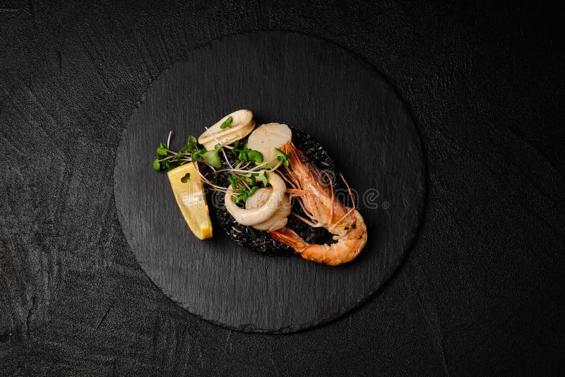 Black Risotto with Crayfish, Squid Rings and Scallop on a Black Plate ...