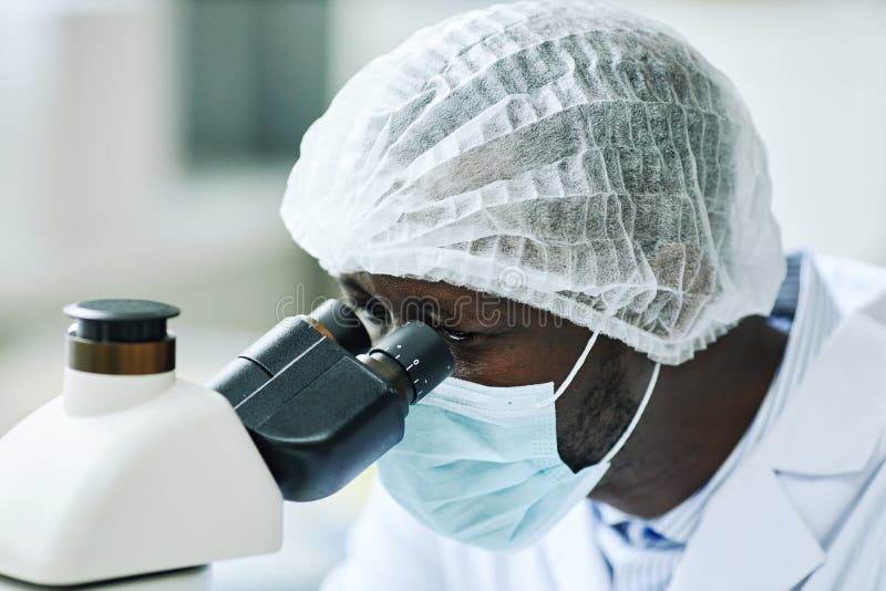 Black Scientist Looking in Microscope Working on Research in Laboratory ...