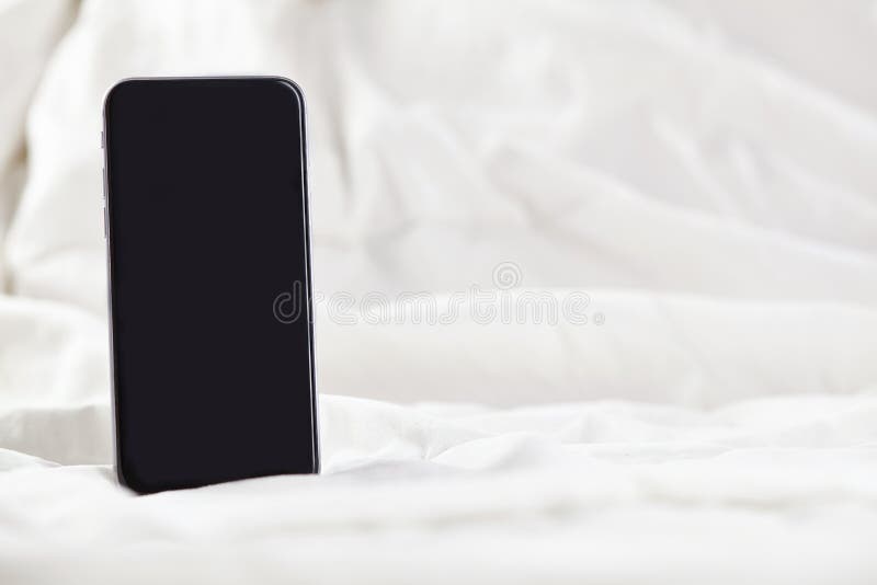 Black Smart Phone on White Bed in the Bedroom. Close Up Stock Image ...