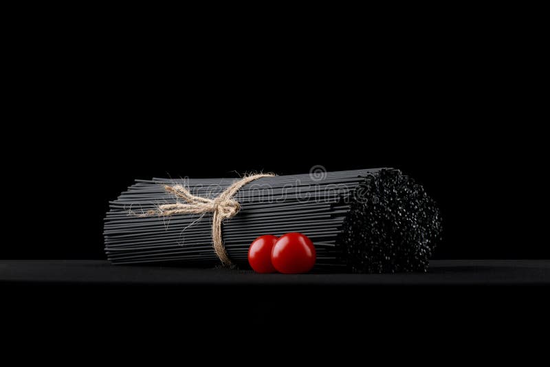 Black Spaghetti Pasta is Raw on a Black Background with Fresh Tomatoes ...