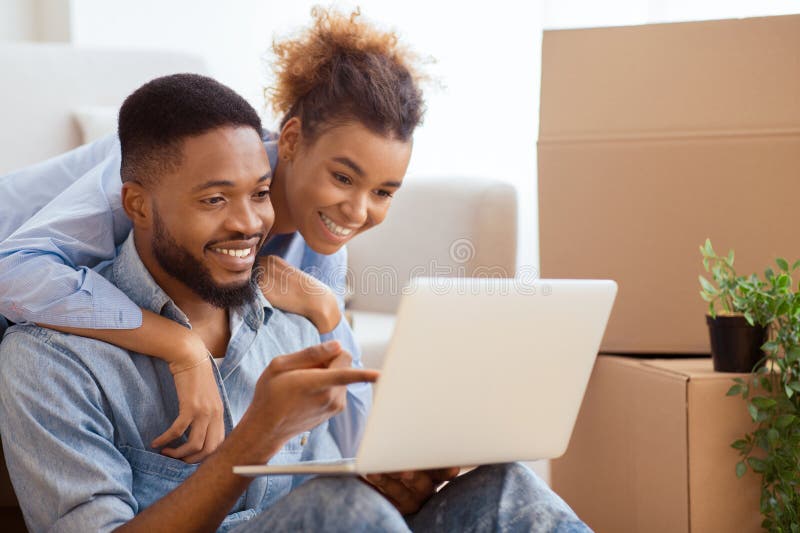 Black Spouses Using Laptop Sitting on Sofa in New Home Stock Photo ...