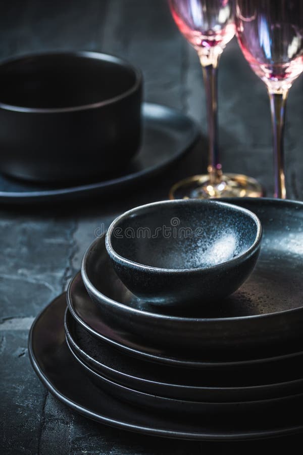 Black Stoneware Plates and Bowls on a Rustic Black Table Stock Image ...