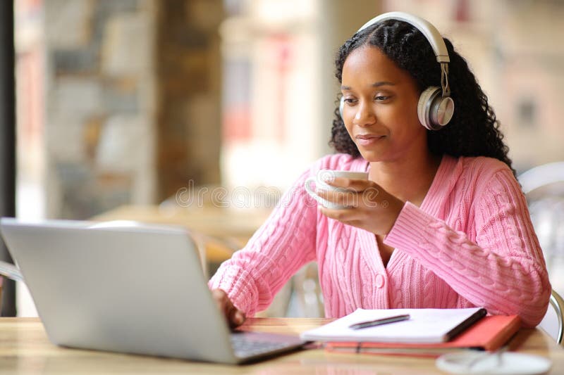 Black Student Studying Using Laptop and Headpone in a Bar Stock Photo ...