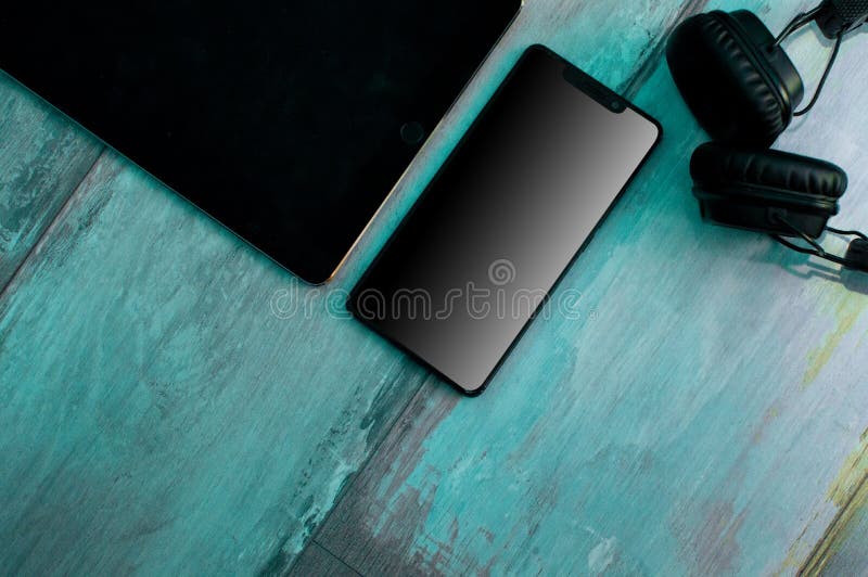 Black Tablet Phone and Headphones Lying on a Blue Table, Copyspace ...