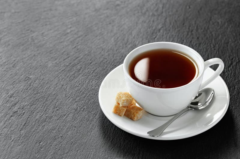 Black Tea in Cup on Saucer with Spoon and Cane Sugar Cubes on Table ...
