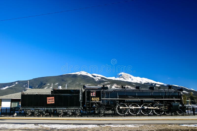 A Black Train is Sitting on the Tracks in Front of a Mountain Editorial ...