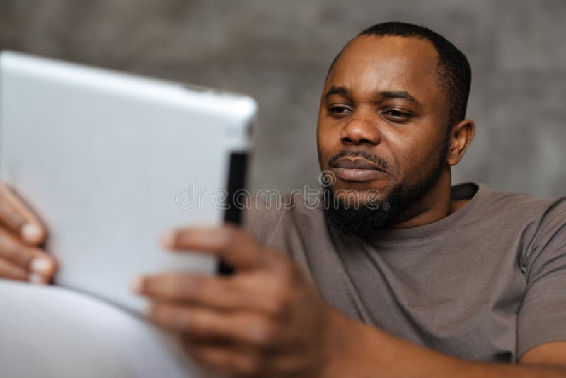 Black Unshaven Man Using Tablet Computer while Sitting on Sofa Stock ...