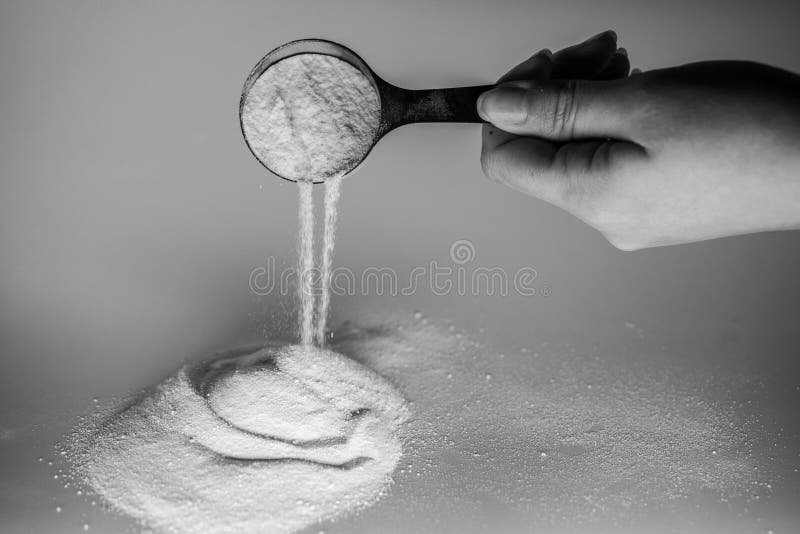 Hand Pouring Flour from a Measuring Spoon in Black and White. Stock ...