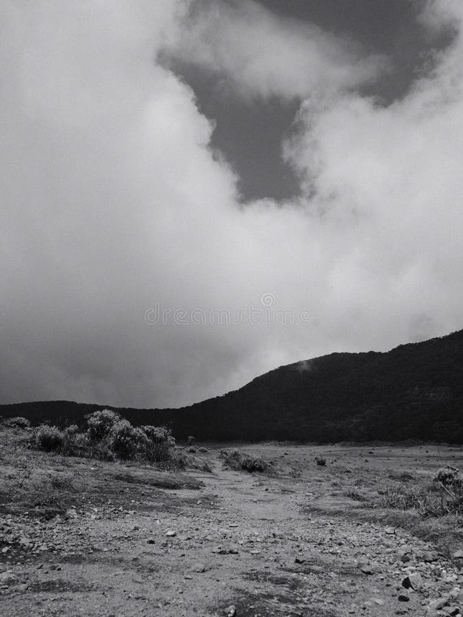 A Black and White Photo of a Desolate Landscape with a Large Cloud in ...