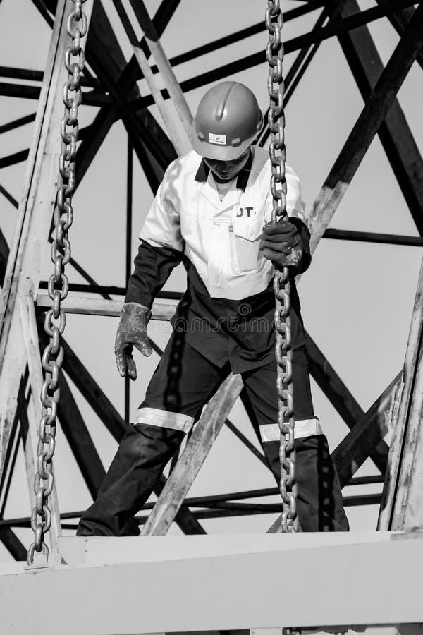 Black and White Shot of a Construction Worker Handling Chains on a High ...