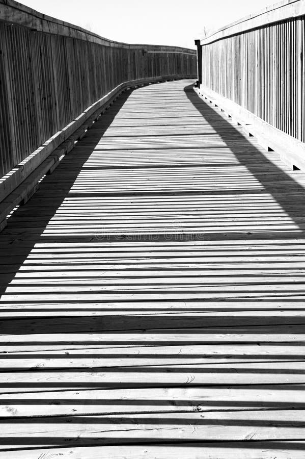Black and White Wooden Walkway with Shadows from the Railing Creating a ...