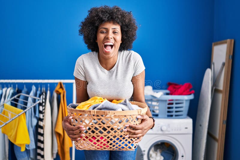 Black Woman With Curly Hair Holding Laundry Basket Smiling And Laughing