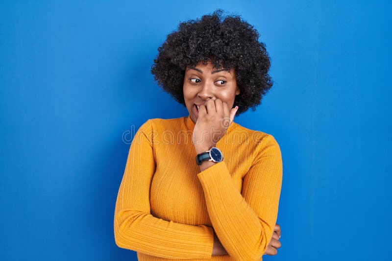 Black Woman With Curly Hair Standing Over Blue Background Looking