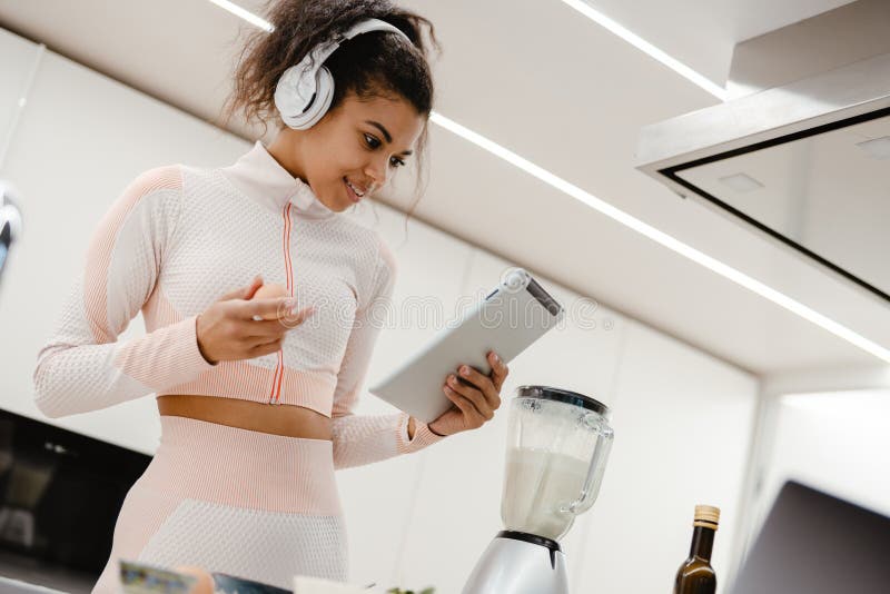 Black Woman in Headphones Using Tablet Computer while Cooking Stock ...