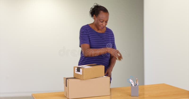 A Black Woman Receiving Package Delivery and Brining it Inside Stock ...