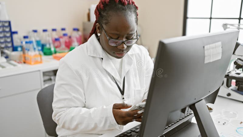 Black Woman Scientist with Braids Using Mobile Phone in Laboratory ...