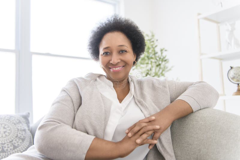 Black Woman Sitting on Sofa at Home with Beautiful Smile Stock Photo ...