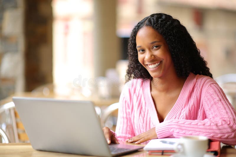 Black Woman Using Laptop Looking at Camera in a Bar Stock Photo - Image ...