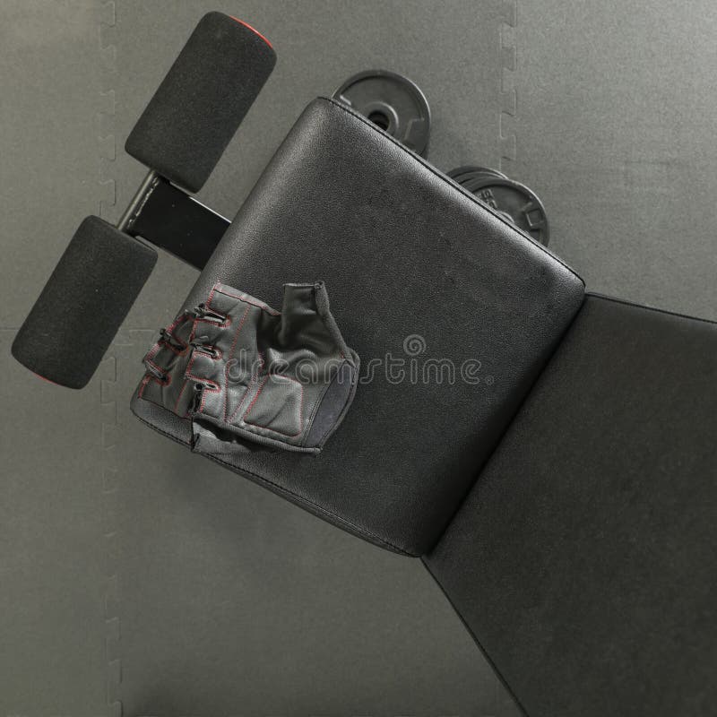 Black Workout Gloves on a Padded Black Exercise Bench on Gray Textured ...